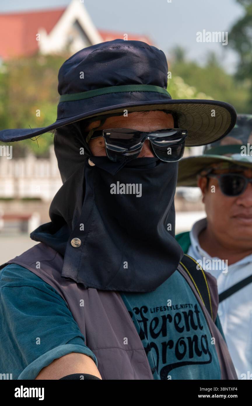 A sun-protected tourist coach park attendant in Vientiane, capital city ...