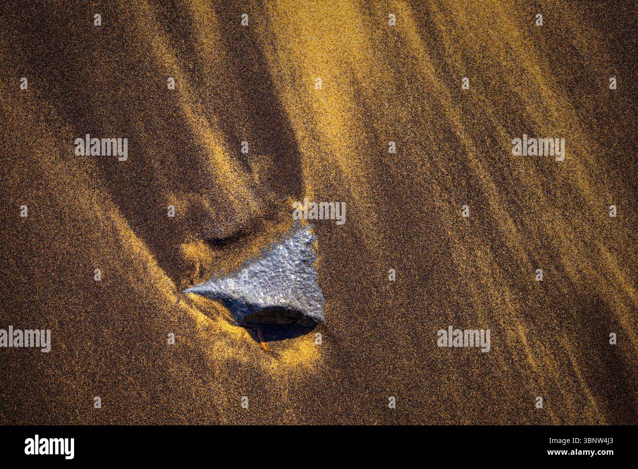Wind blowing sand grains of different colors creating streaks in the ...