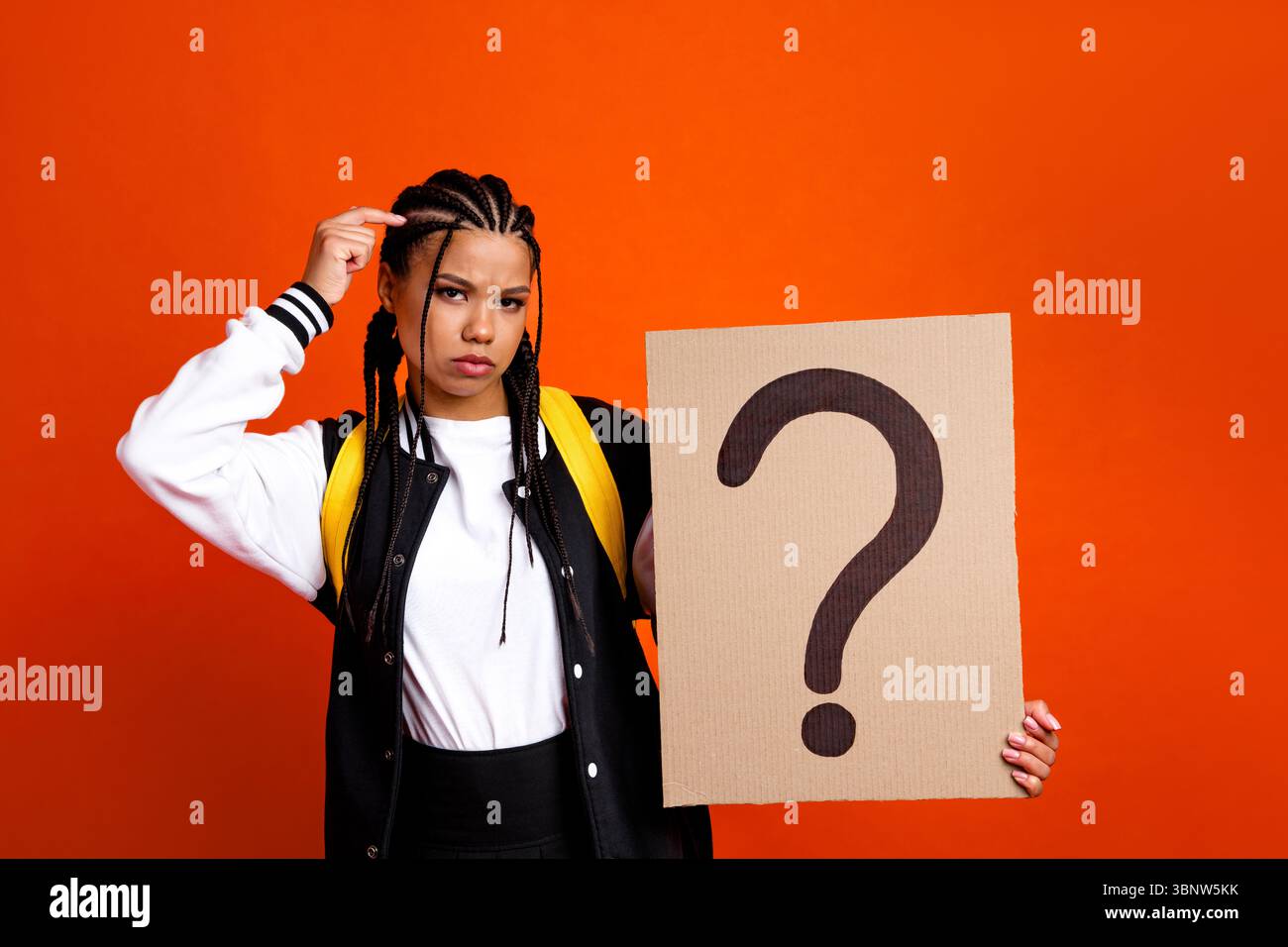 Teen student holding a question mark sign on an orange background ...