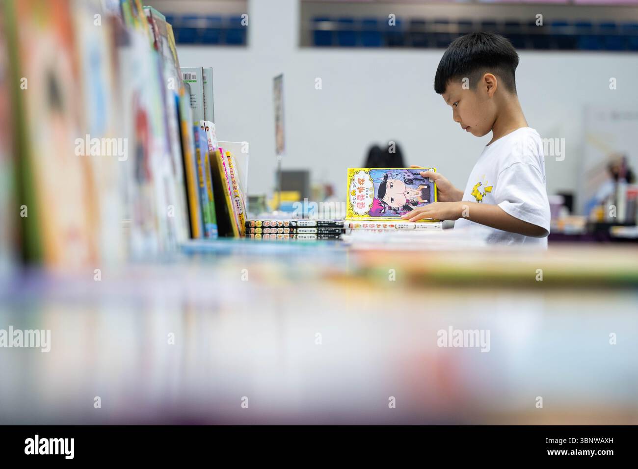 Macao. 4th July, 2025. A child reads a book at the 28th Macao Book ...