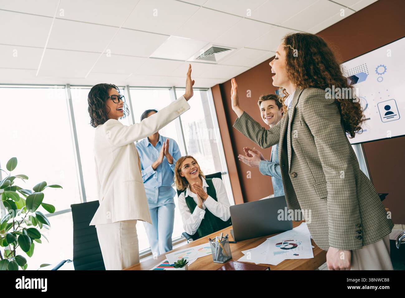 Team celebrating success with high-five in professional office setting ...