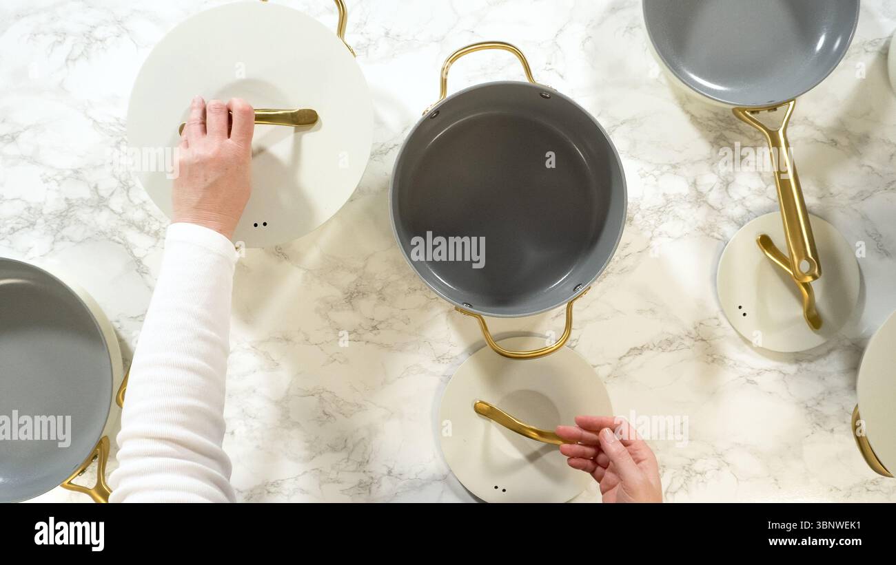 Placing lid on cookware with gold handle Stock Photo - Alamy