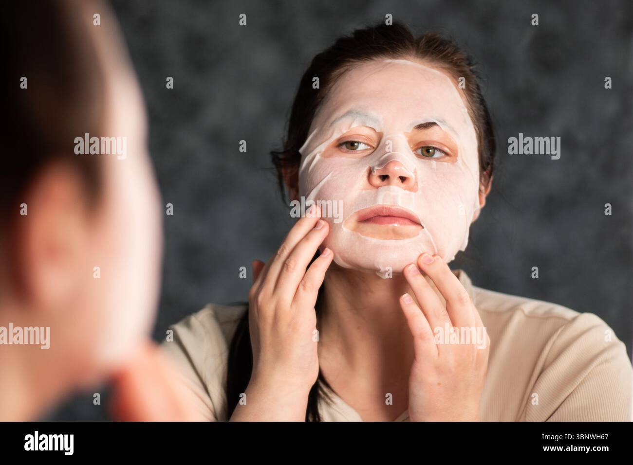 Side view of female carefully placing facial sheet mask. Useful for demonstrating proper ...