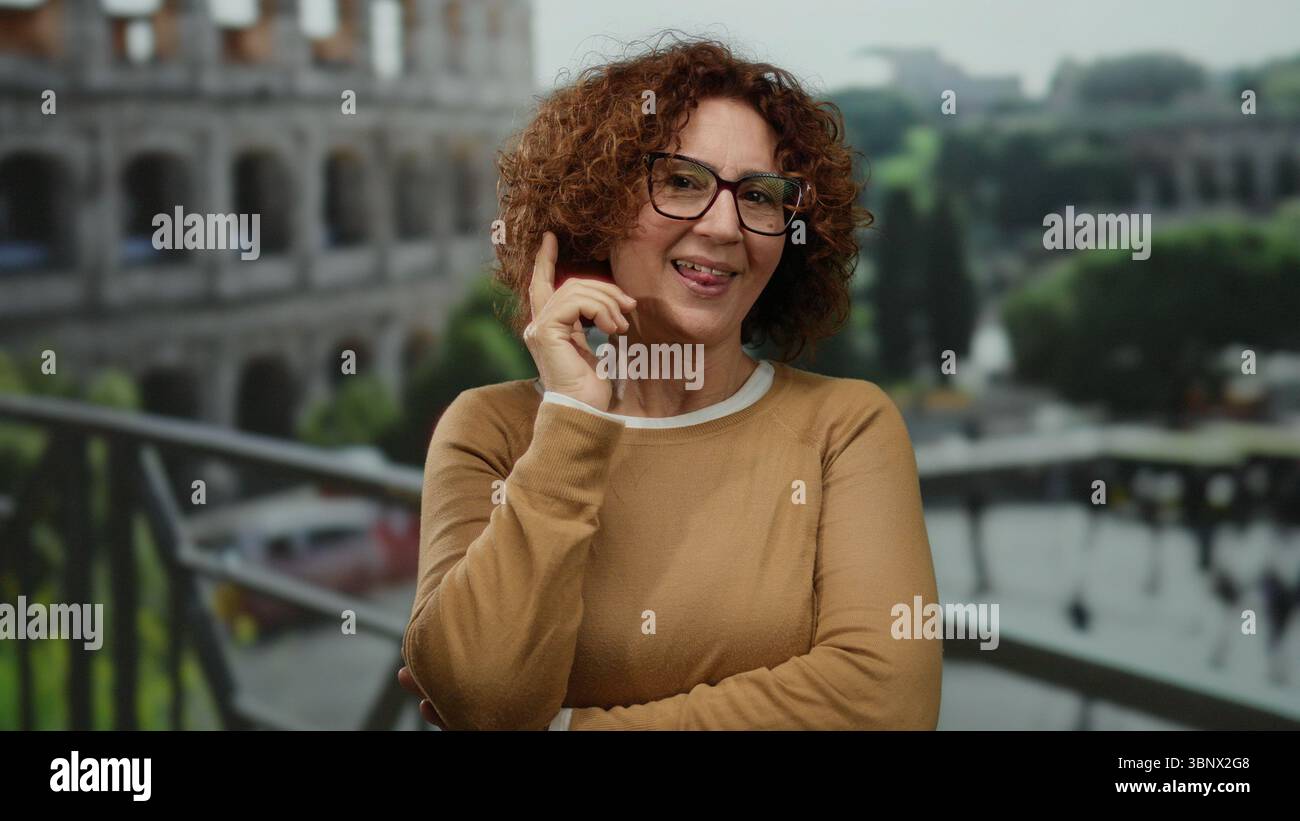Woman smiling at roman coliseum with curly hair in brown sweater ...