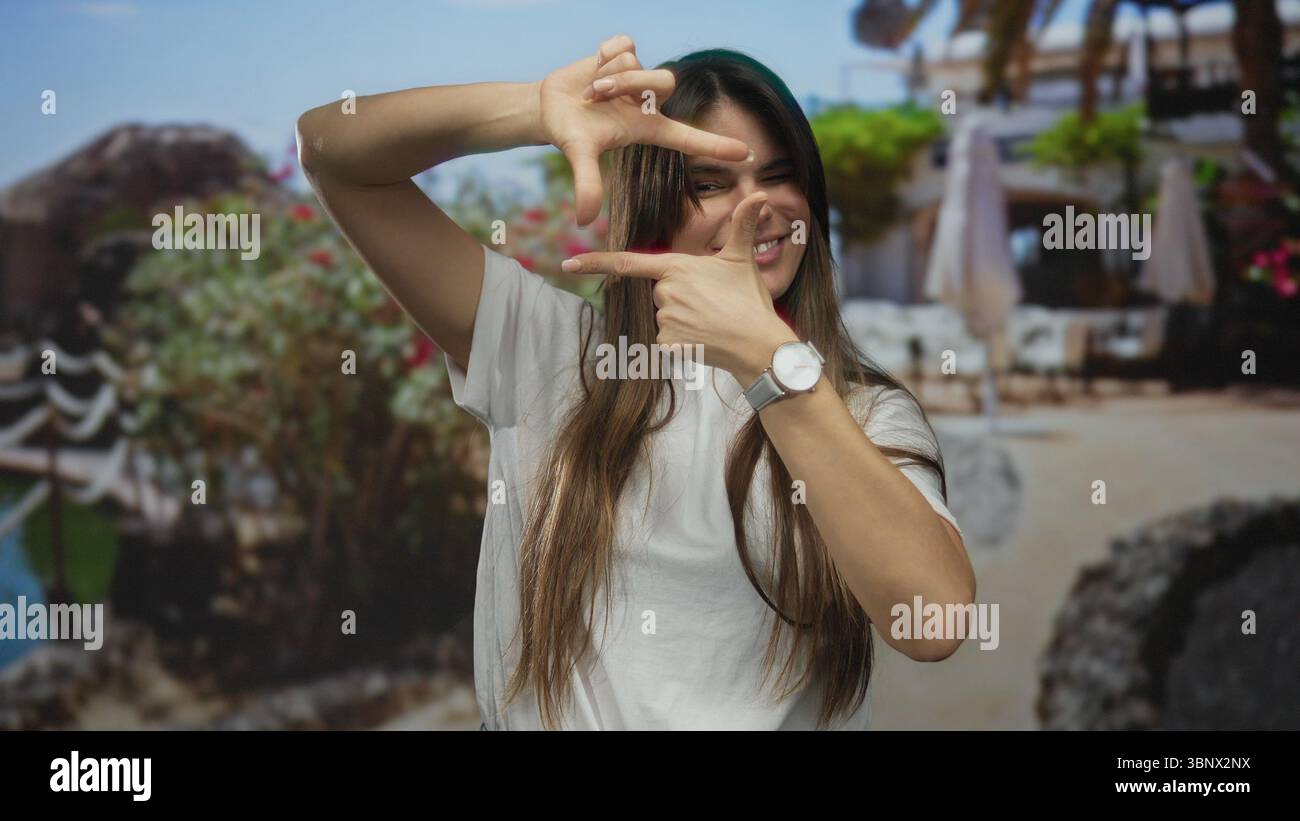 Woman smiling on a sunny beach making a frame gesture with her hands ...