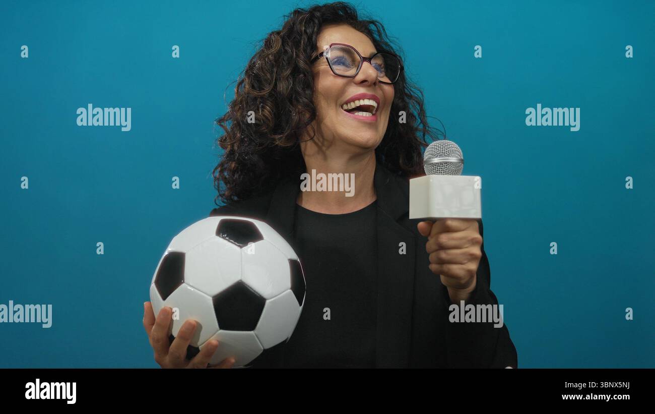 Woman holding microphone and soccer ball against blue background ...