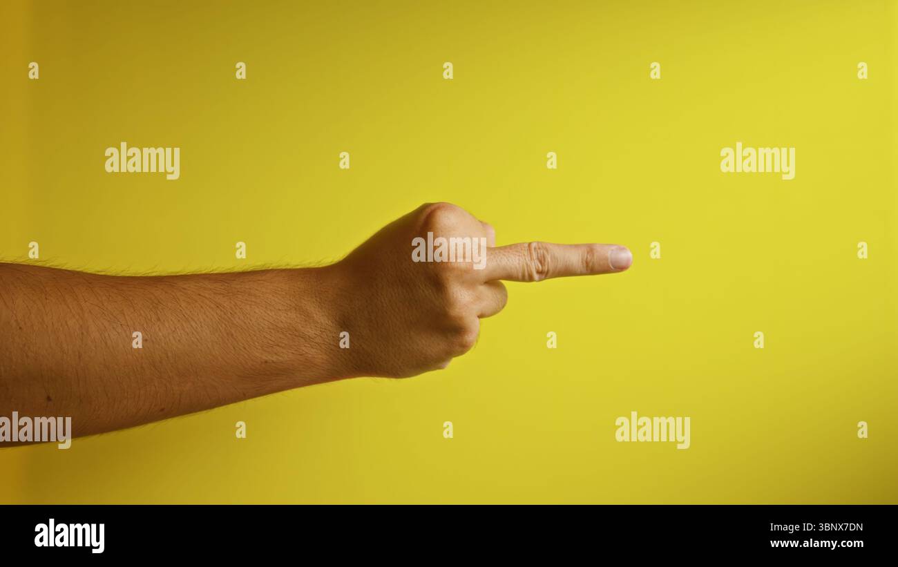 Man's hand showing middle finger against a yellow background in a rude ...