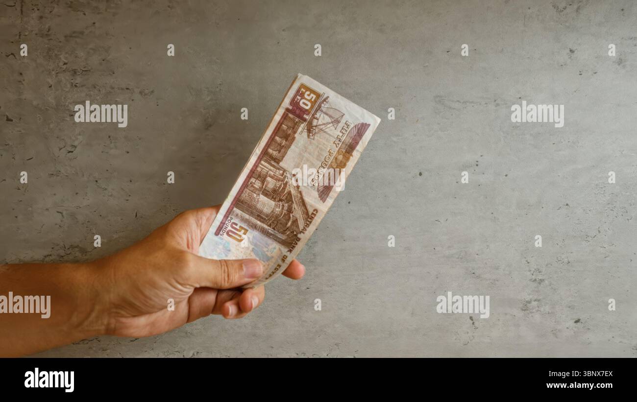 Hand holding egyptian pounds against a concrete background Stock Photo ...