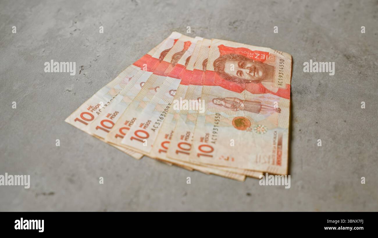 Colombian 10,000 peso banknotes fanned out on a concrete surface ...