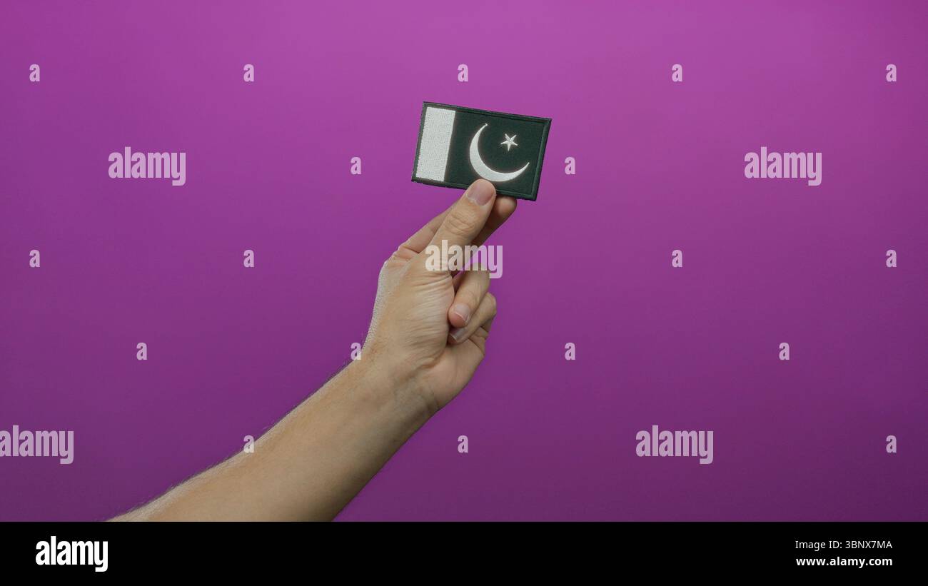 Man hand holding pakistan flag embroidery on pink background ...