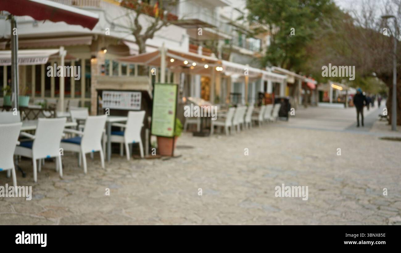 Defocused promenade in mallorca with blurred chairs and tables lining a ...