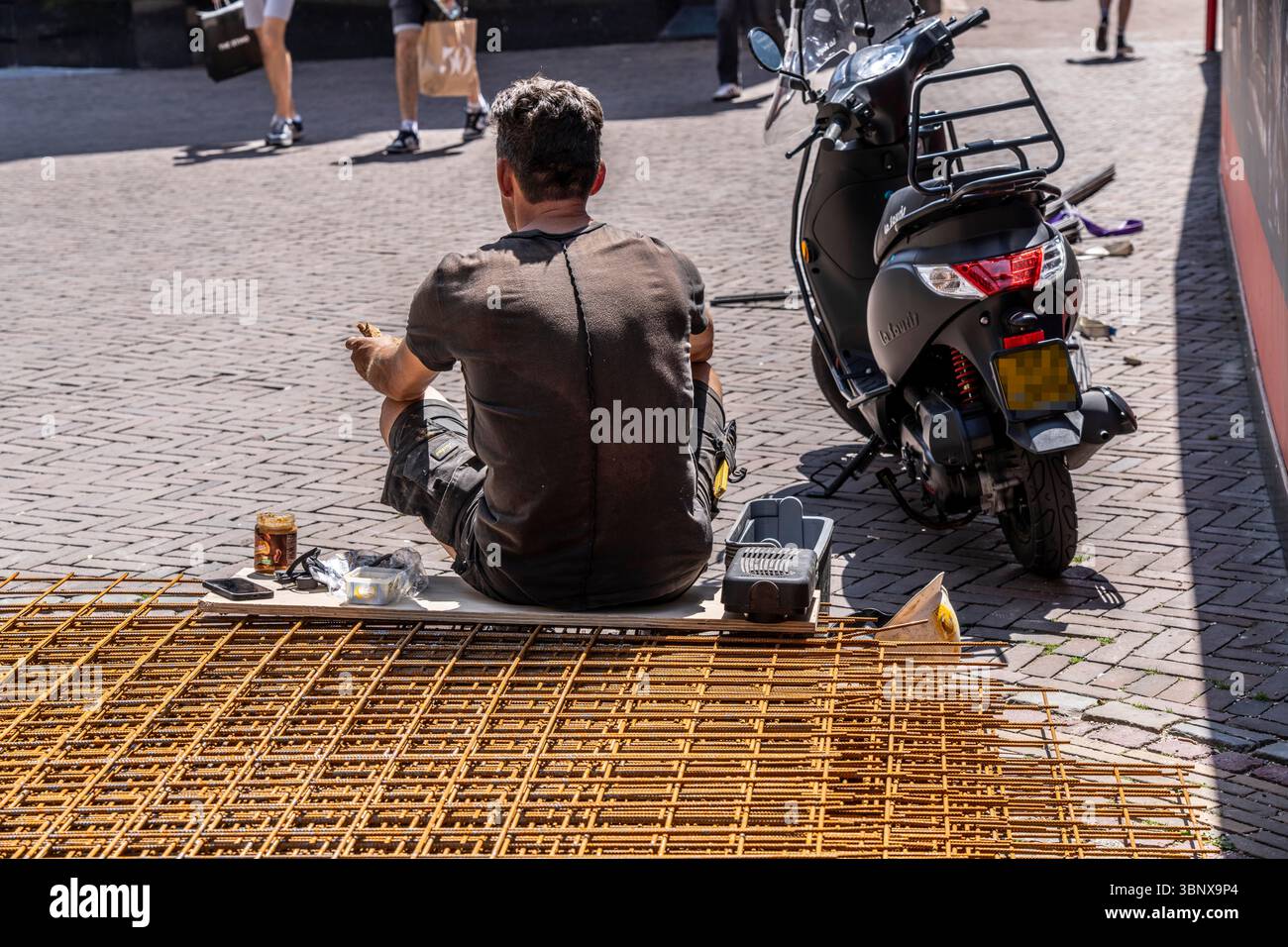 Construction workers taking their lunch break, sitting on wire mesh in ...