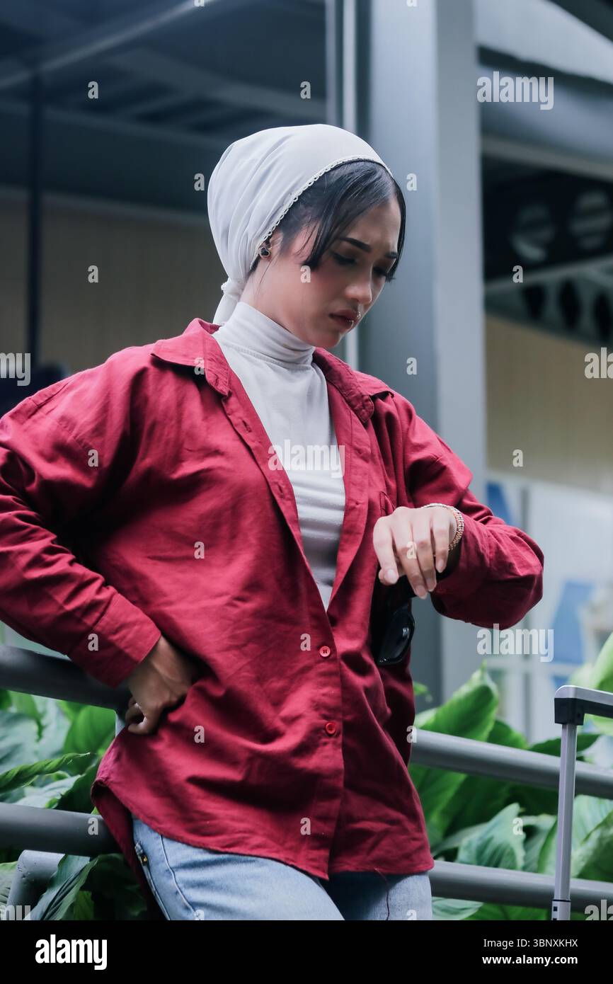 A modern woman in a hijab checks the time, creating a moment of ...