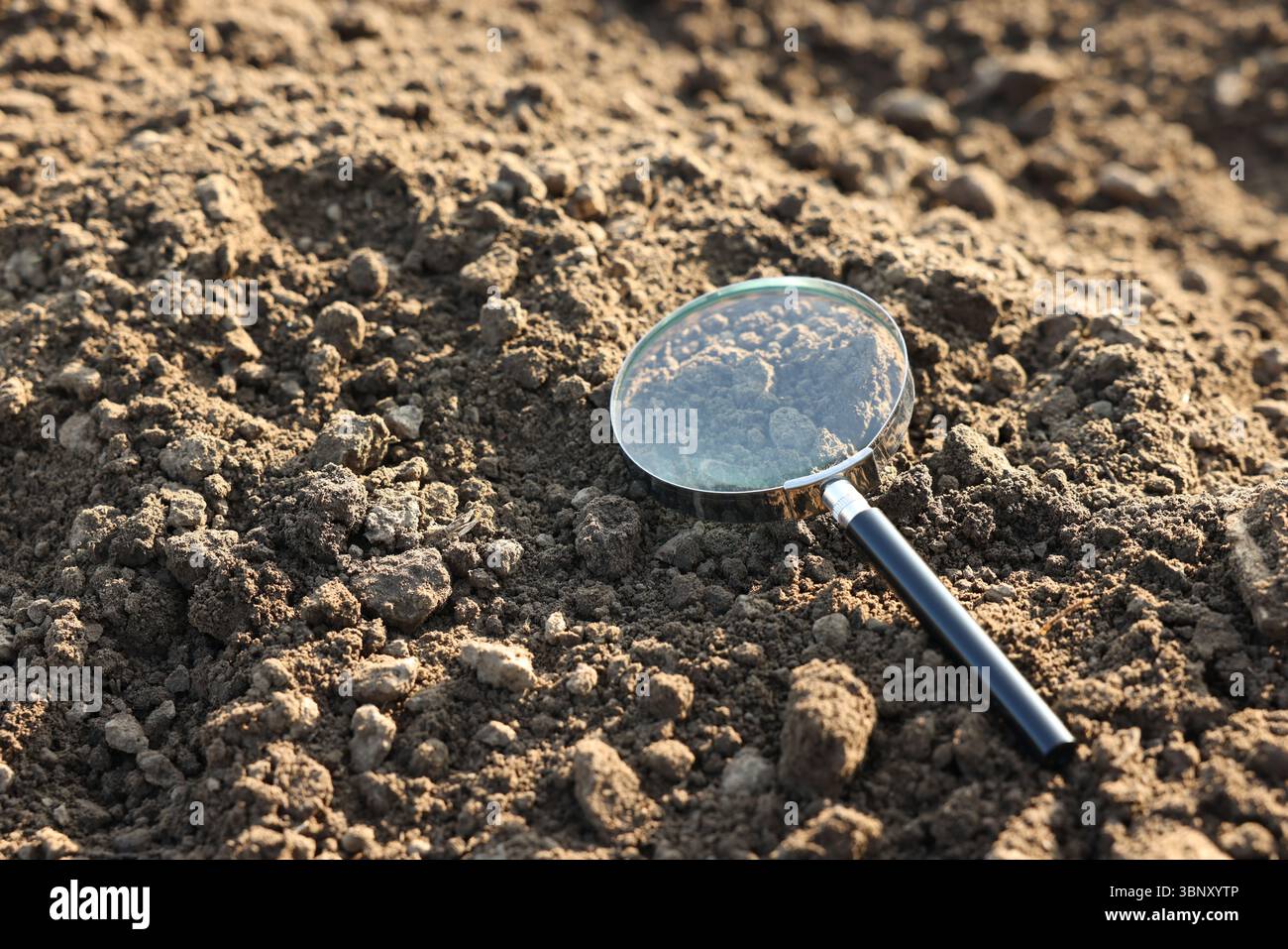 Magnifying glass on dry soil in field, space for text Stock Photo - Alamy