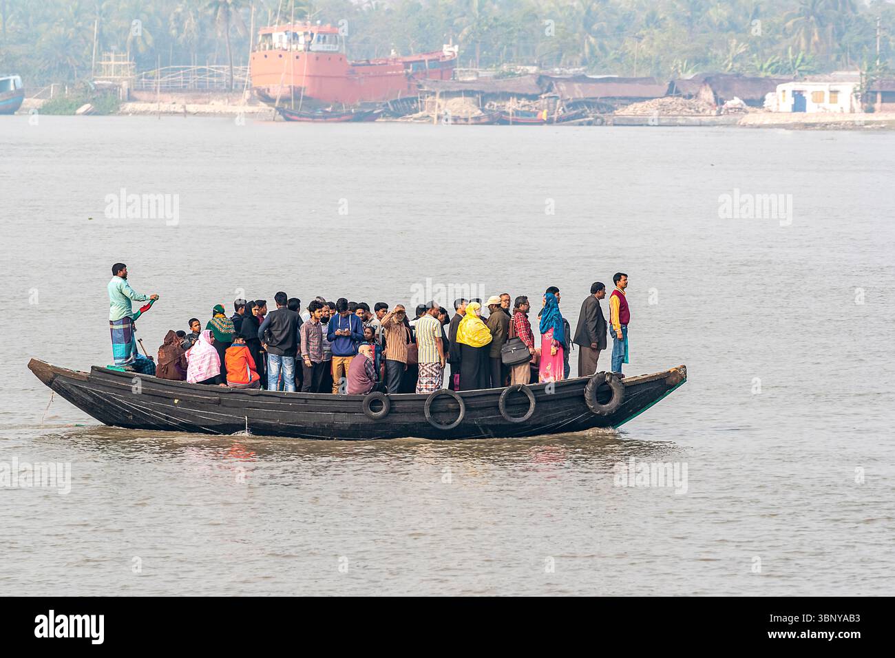 A large group of local people crowded on a traditional wooden ferry ...