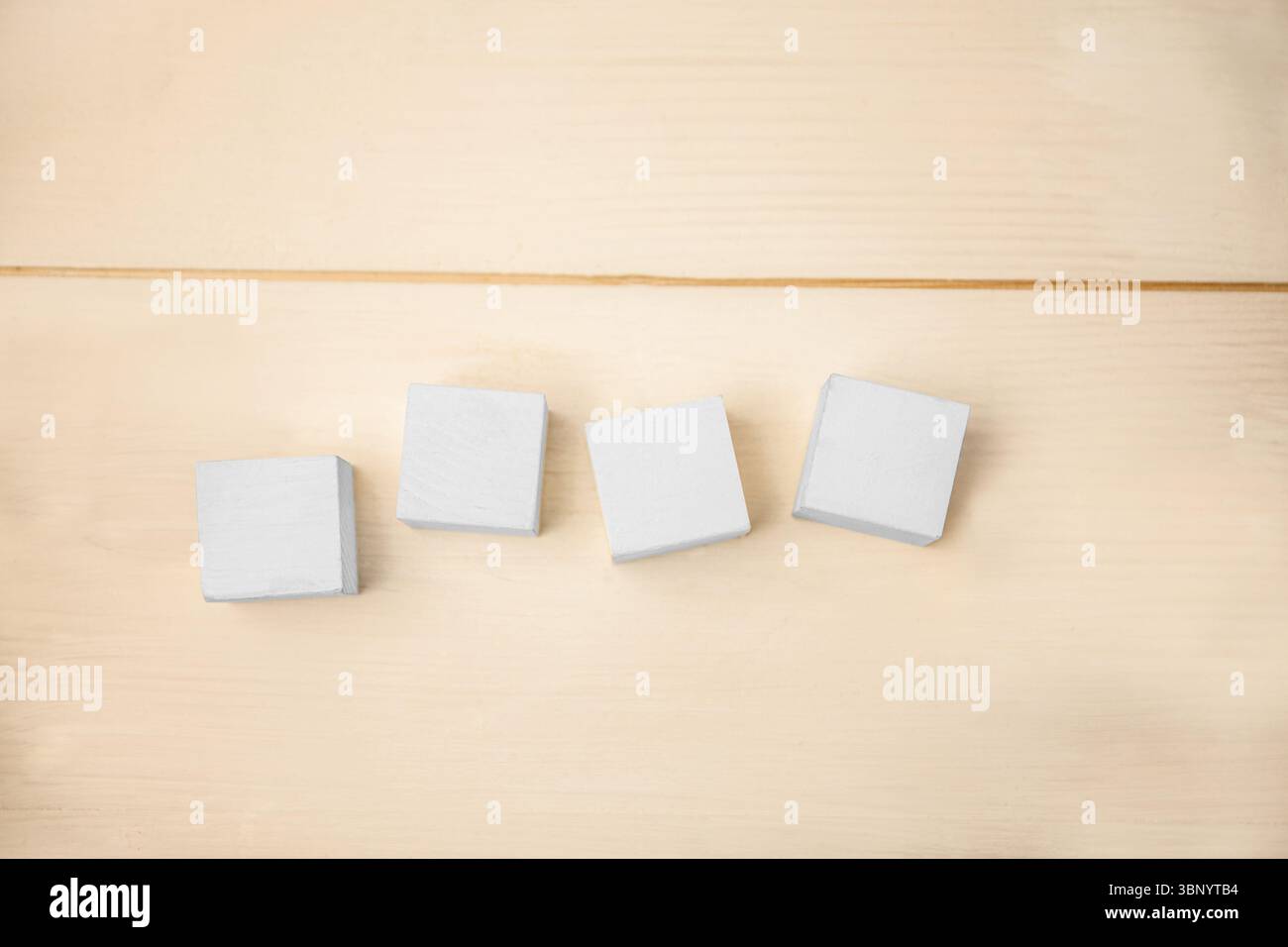 Flat wood tabletop is showing four rotating white square blocks over ...