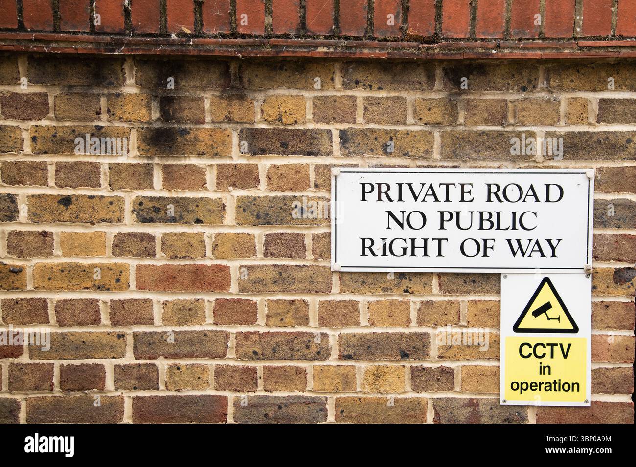 Warning signs mounted on a brick wall: one reading “Private Road No ...