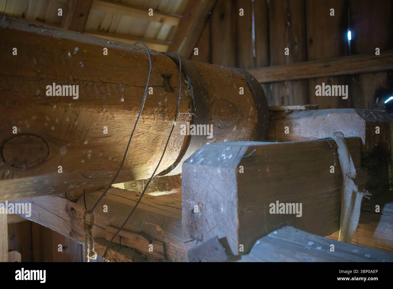 A wooden beam with a rope tied to it. The beam is in a barn Stock Photo ...