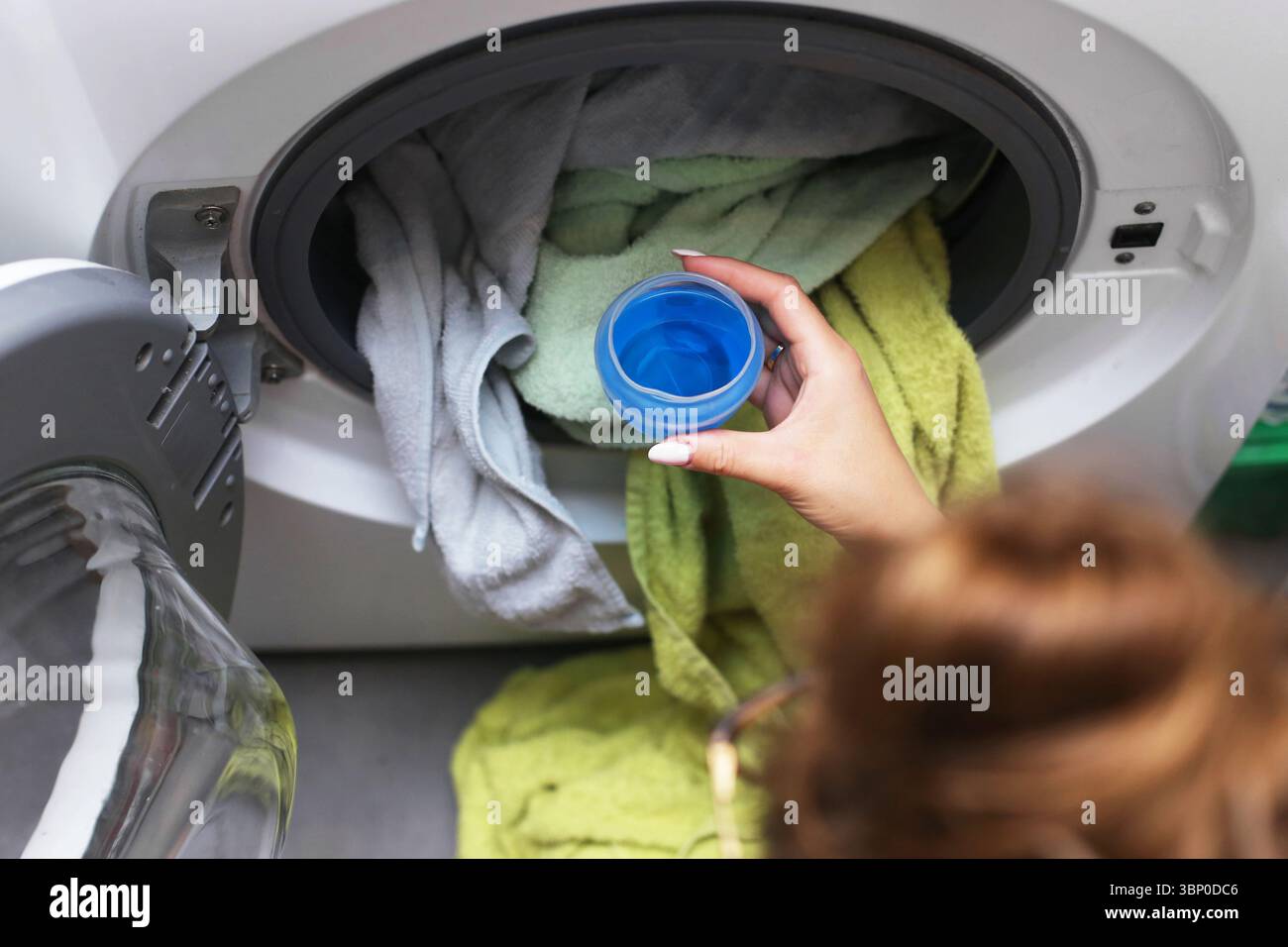 Woman doing laundry at home. Hand holding detergent cup. Open washing ...