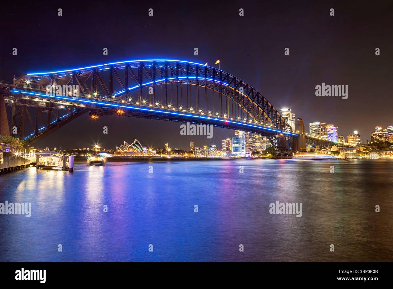 Bright Vivid Sydney lights reflection in blurred waters of Sydney harbour at night in Australia ...