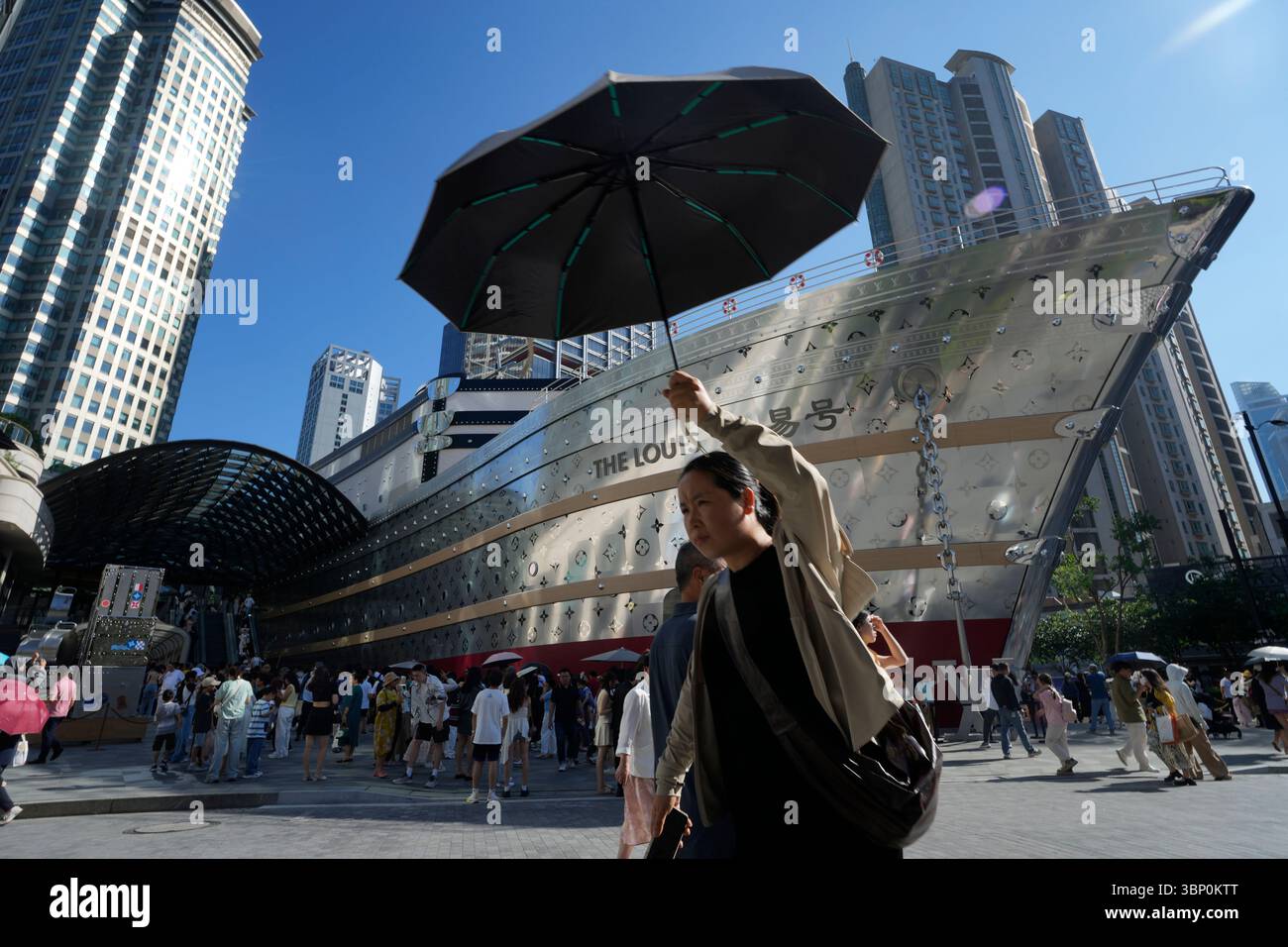 A woman walks with an umbrella past Louis Vuitton's ship-shaped store ...