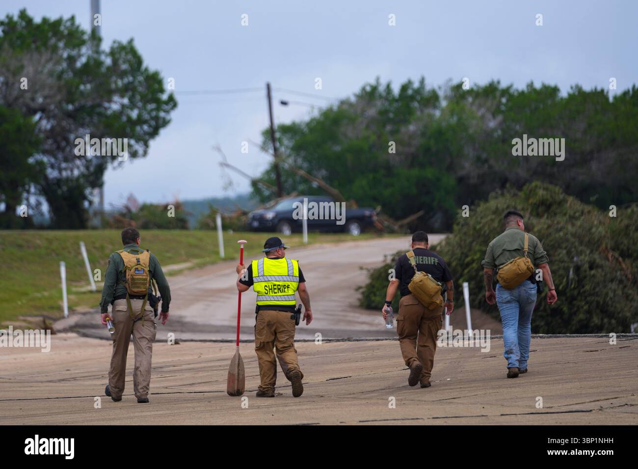 Deputies walk along a road near the Guadalupe River after a flash flood swept through the area ...