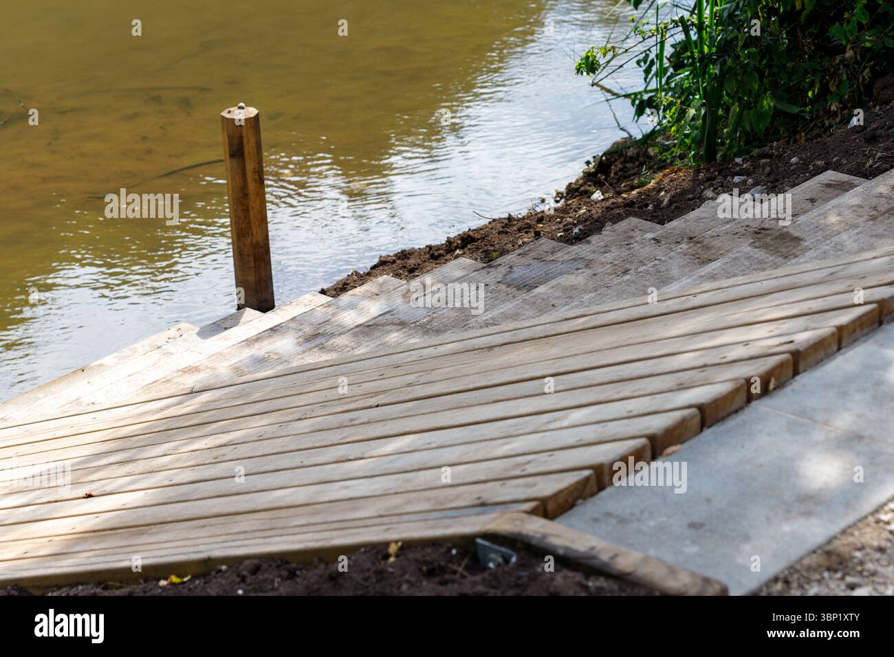 Wooden steps lead from a body of water to a grassy bank. A single ...