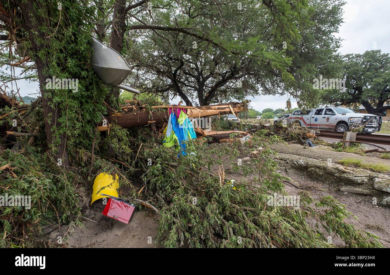 A bent canoe and debris are stuck high in a tree along the banks of the ...