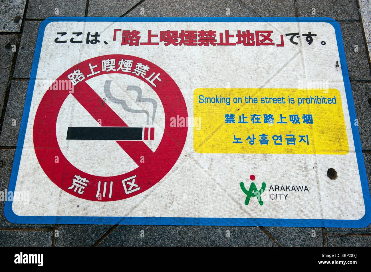 A sidewalk no smoking sign in four languages reminds pedestrians that ...
