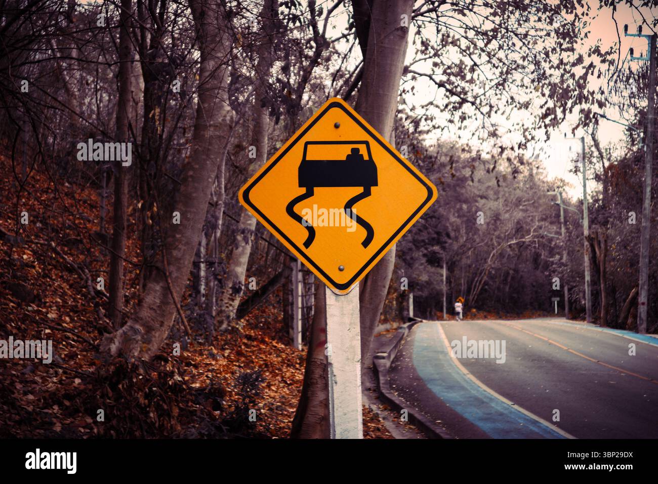 Road safety awareness Yellow slippery road warning sign on a mountain ...
