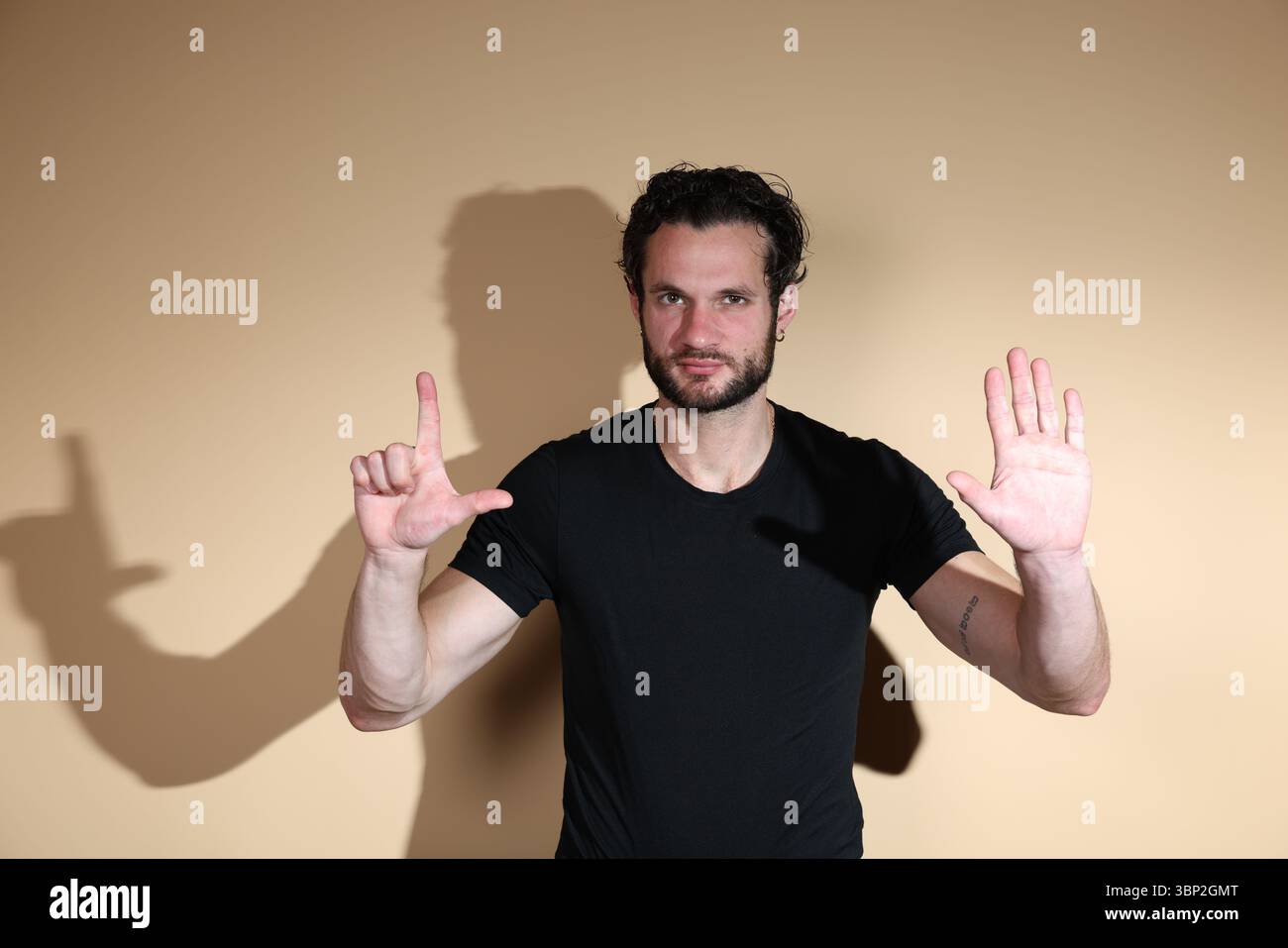 An assertive young man looks directly at the camera, simultaneously ...