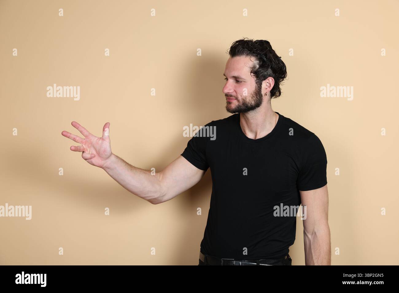 A young man in a black t-shirt displays four fingers on his hand while ...