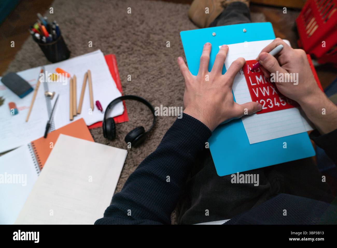 Male student using stencil to write letters and numbers while preparing ...