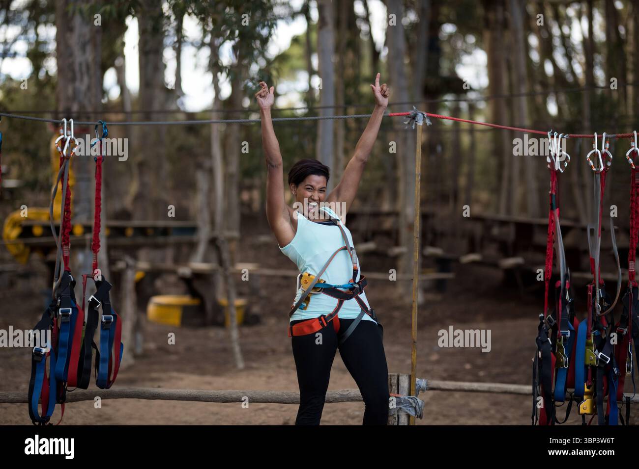 African American woman wearing safety harness and celebrating on forest ...