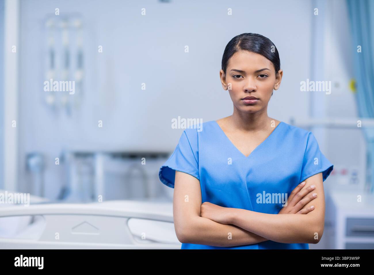 Female nurse standing confidently with arms crossed in hospital room ...