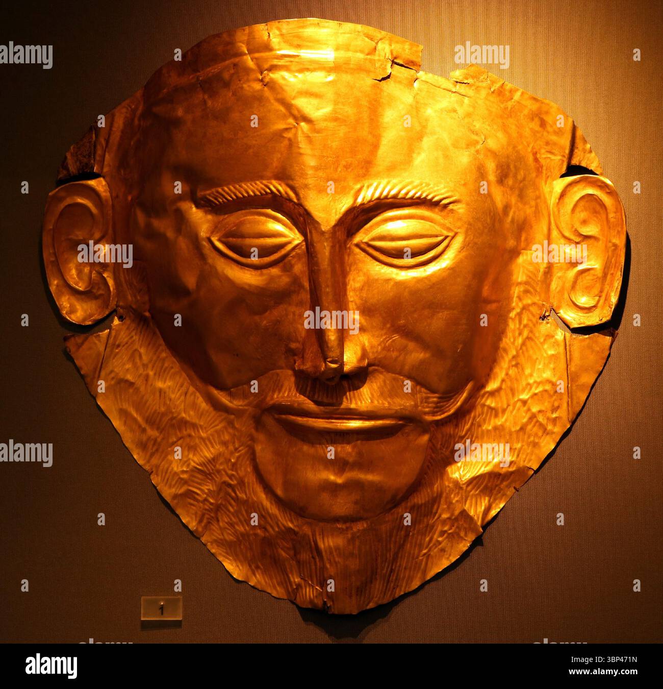 A photograph of the 'Mask of Agamemnon,' a Mycenaean gold funerary mask ...
