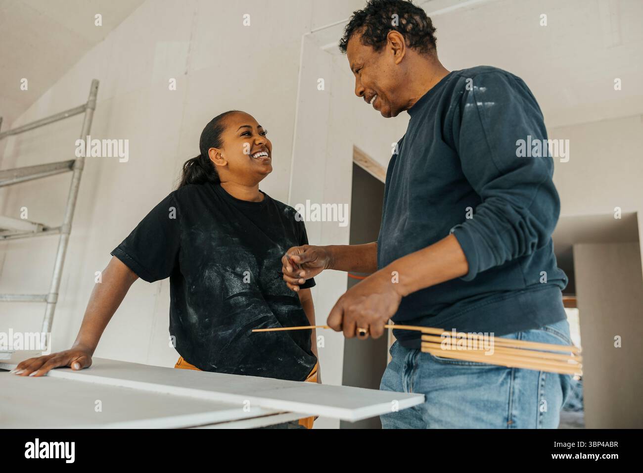 Low angle view of smiling male and female construction workers talking ...