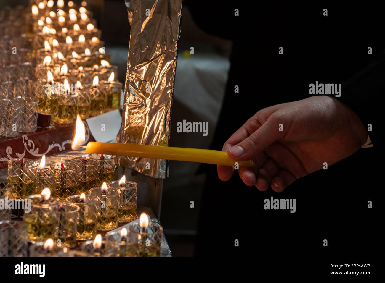 An Orthodox, haredi, Jewish man uses a long, wax, yellow taper candle ...