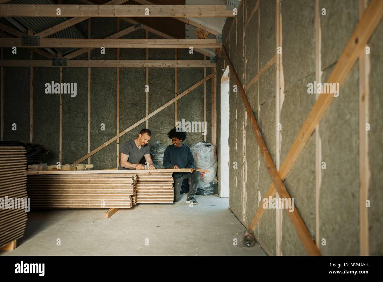 Father teaching son to mark measurements on wooden plank at renovation ...