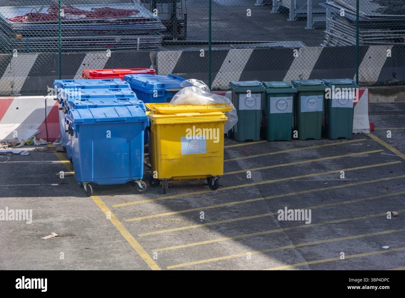 Different colored industrial waste bins stand in a designated area of a ...