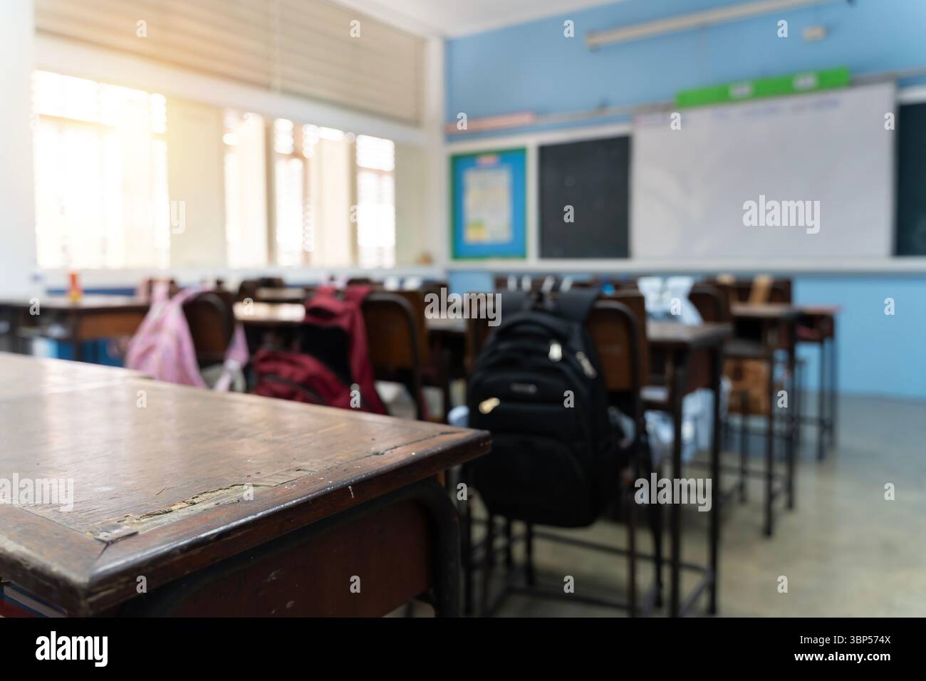 Vintage wooden desks and chairs with student backpacks in empty ...