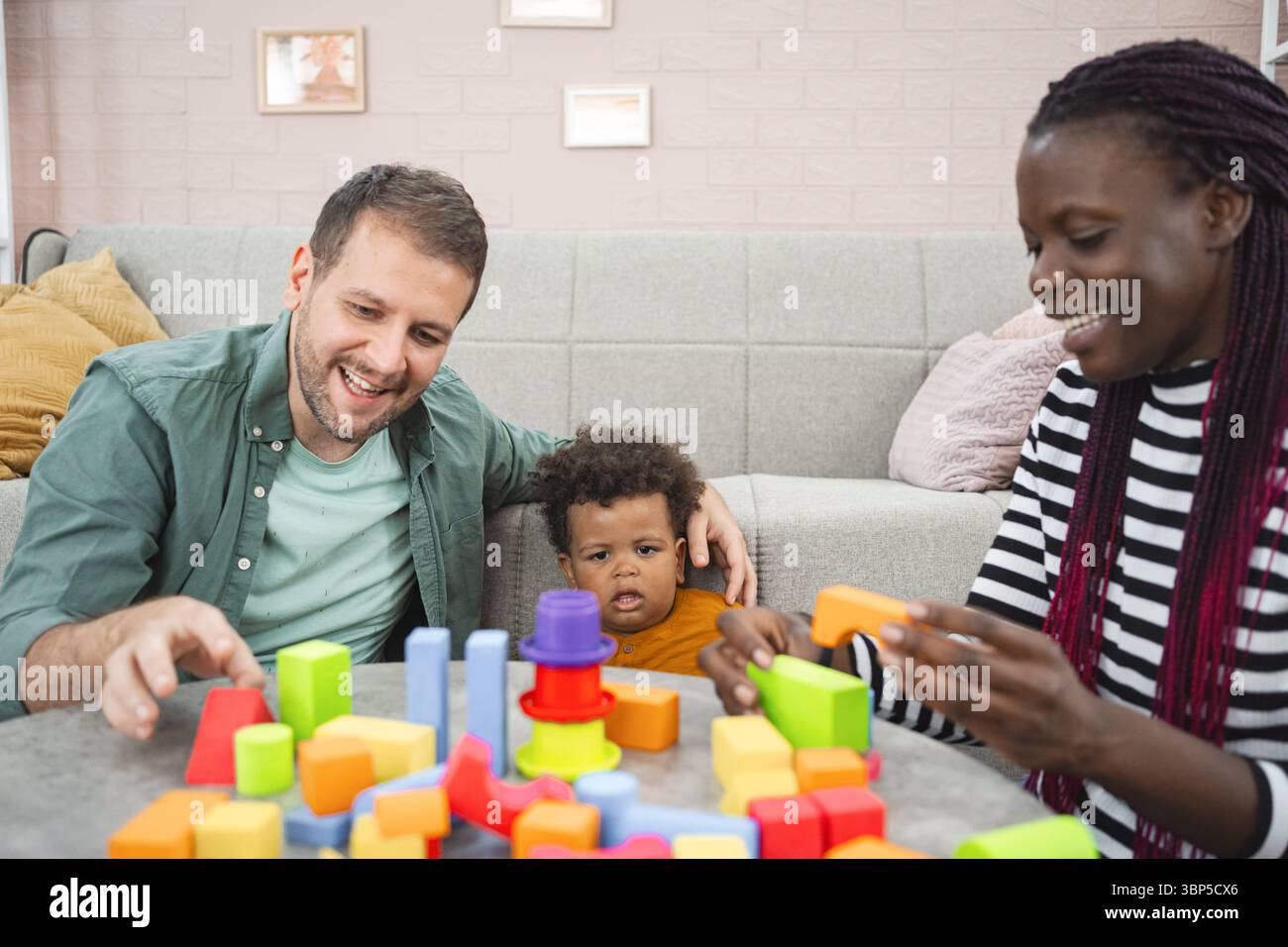 Family engaging in playtime with colorful building blocks indoors Stock ...