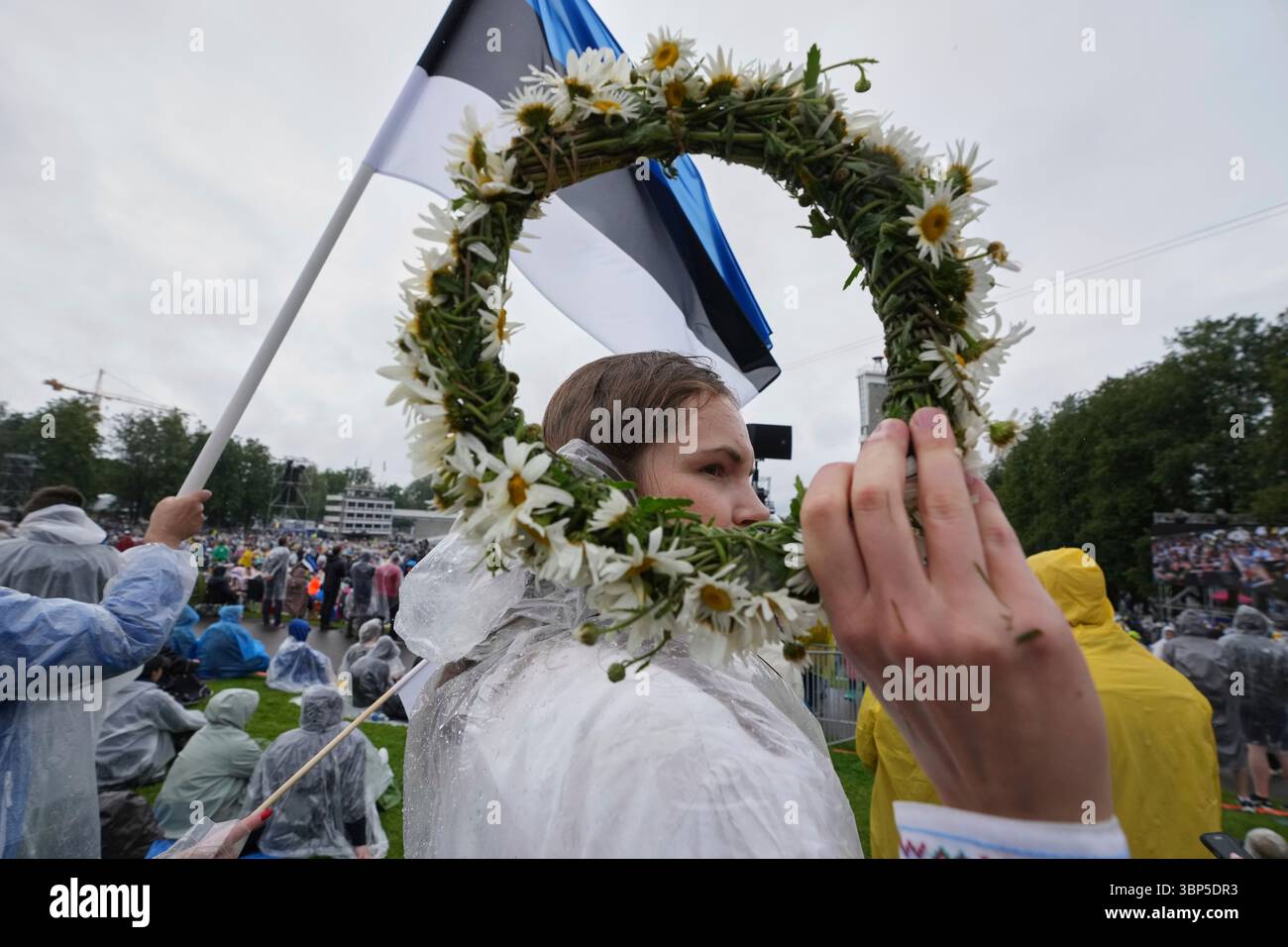 A woman adjusts her wreath of flowers during the song festival, part of ...