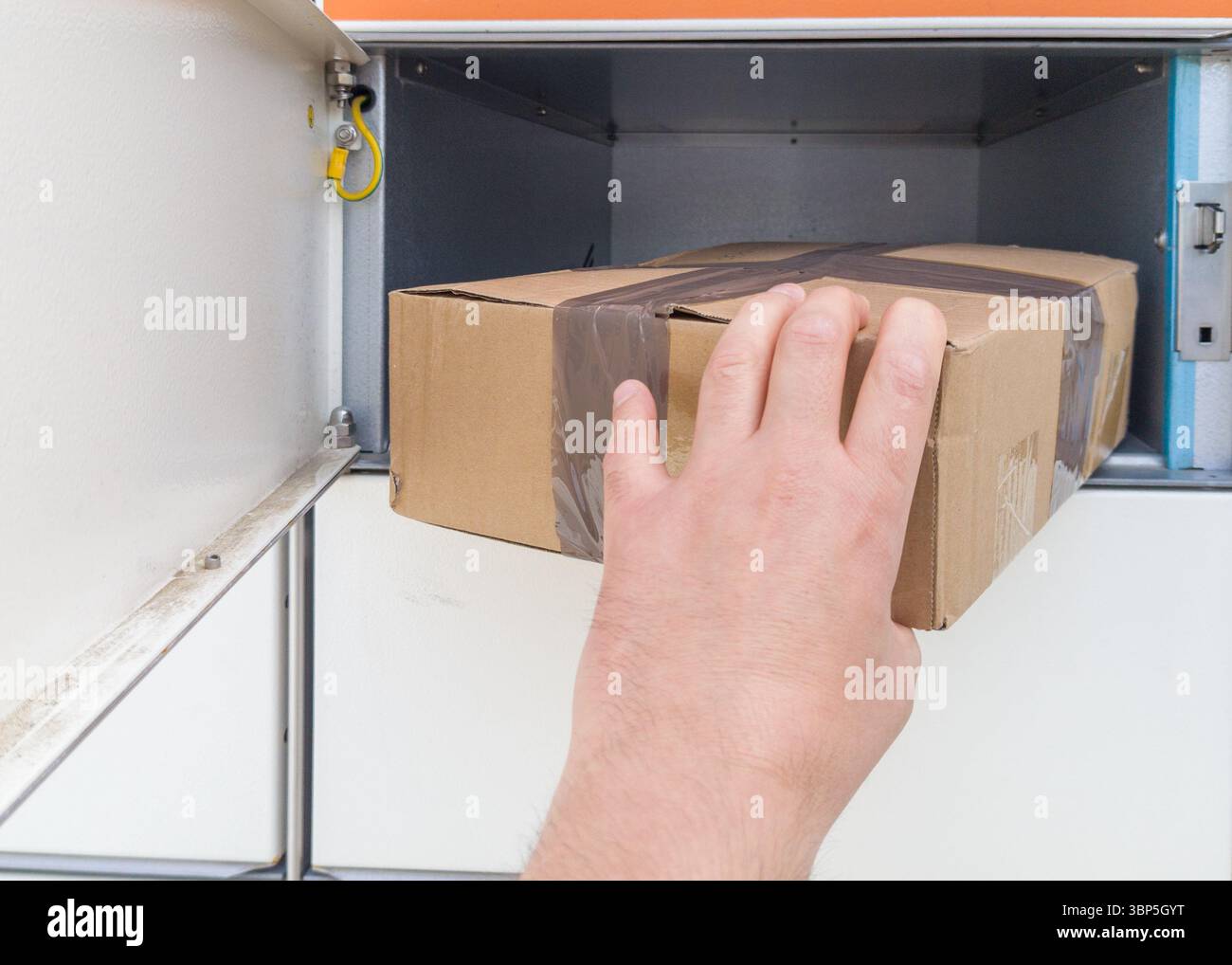 Hand collecting cardboard package from locker Stock Photo - Alamy
