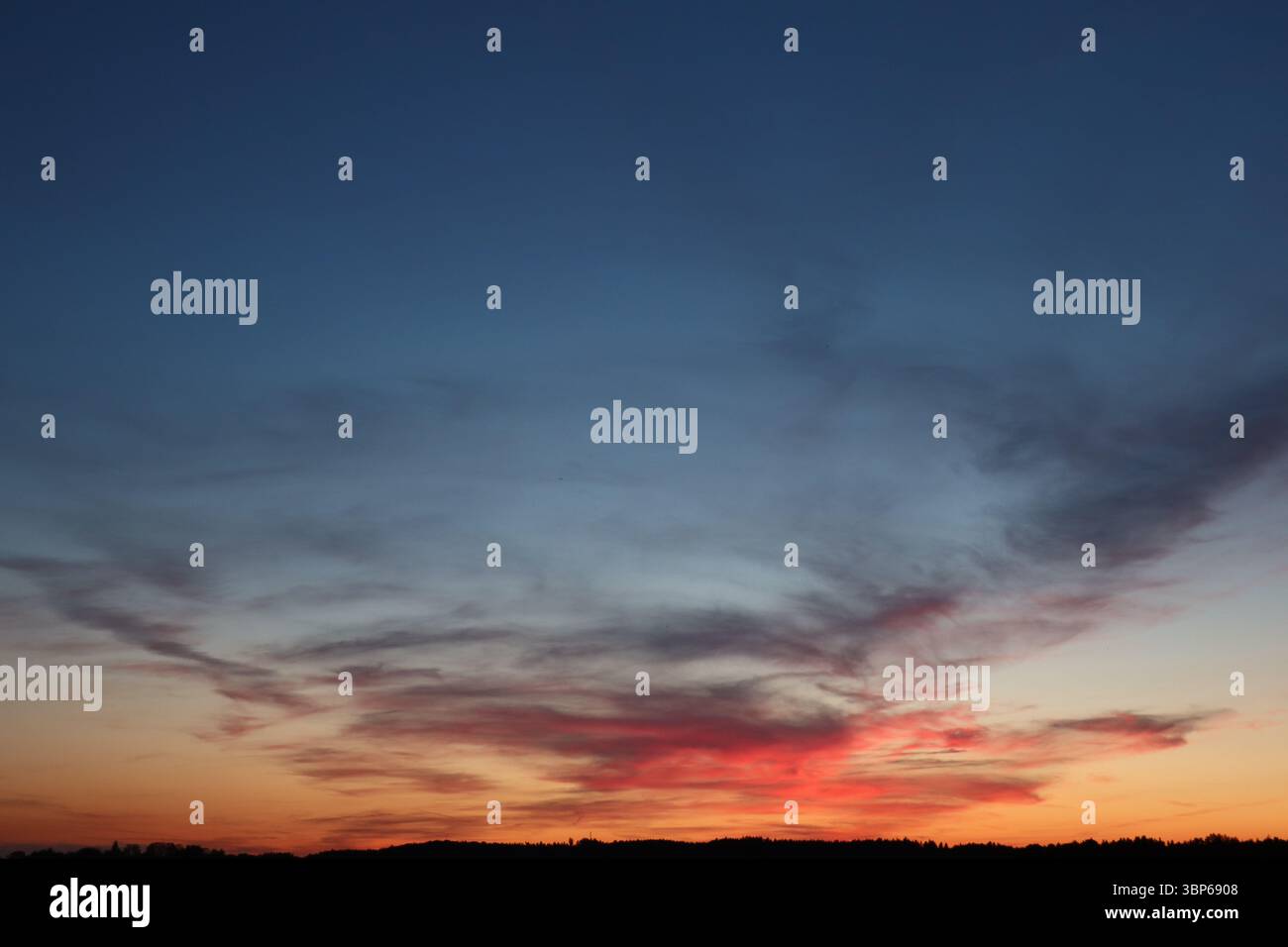 Evening sky transitioning from deep blue to warm orange and red above ...