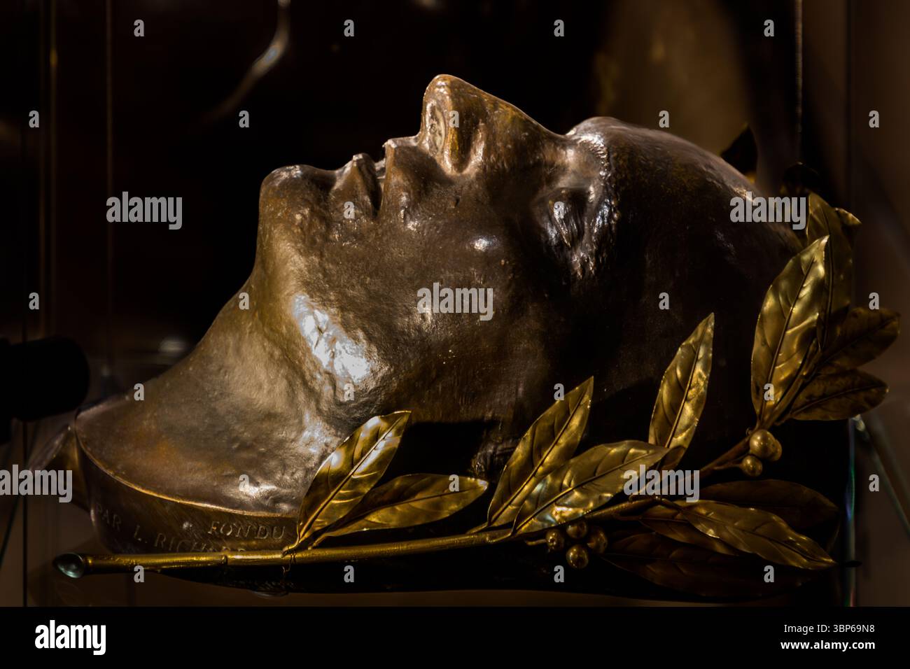 A bronze death mask of Napoleon III, adorned with a golden laurel ...