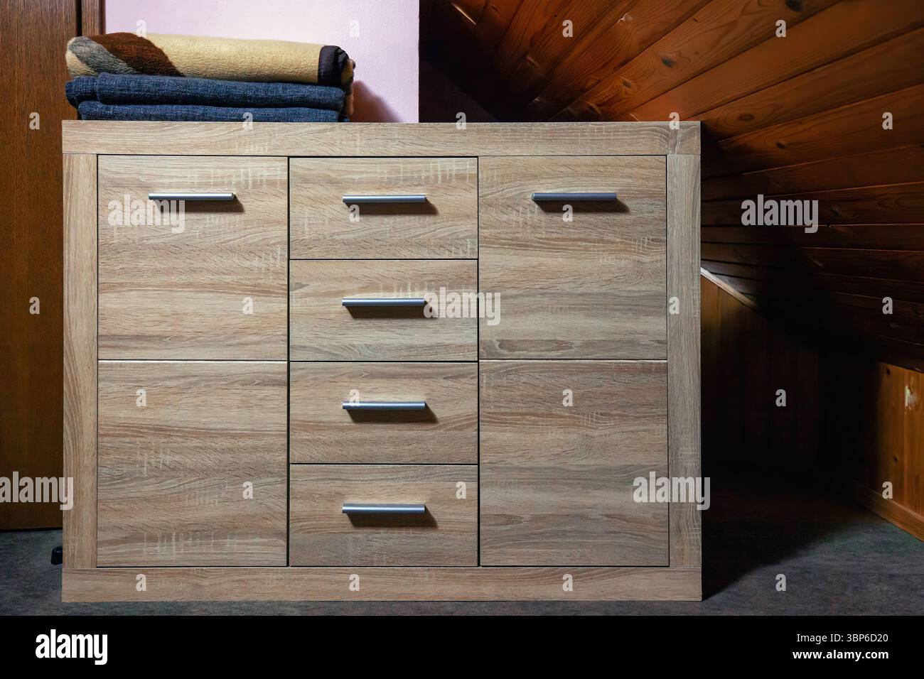 Wooden chest of drawers with folded blankets on top in small attic ...
