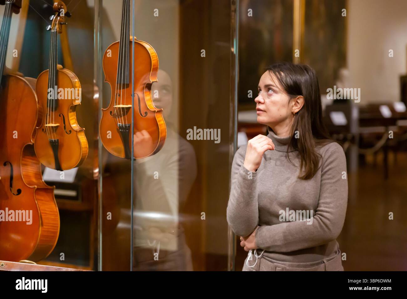 Interested brunette visiting exhibition of medieval musical instruments ...