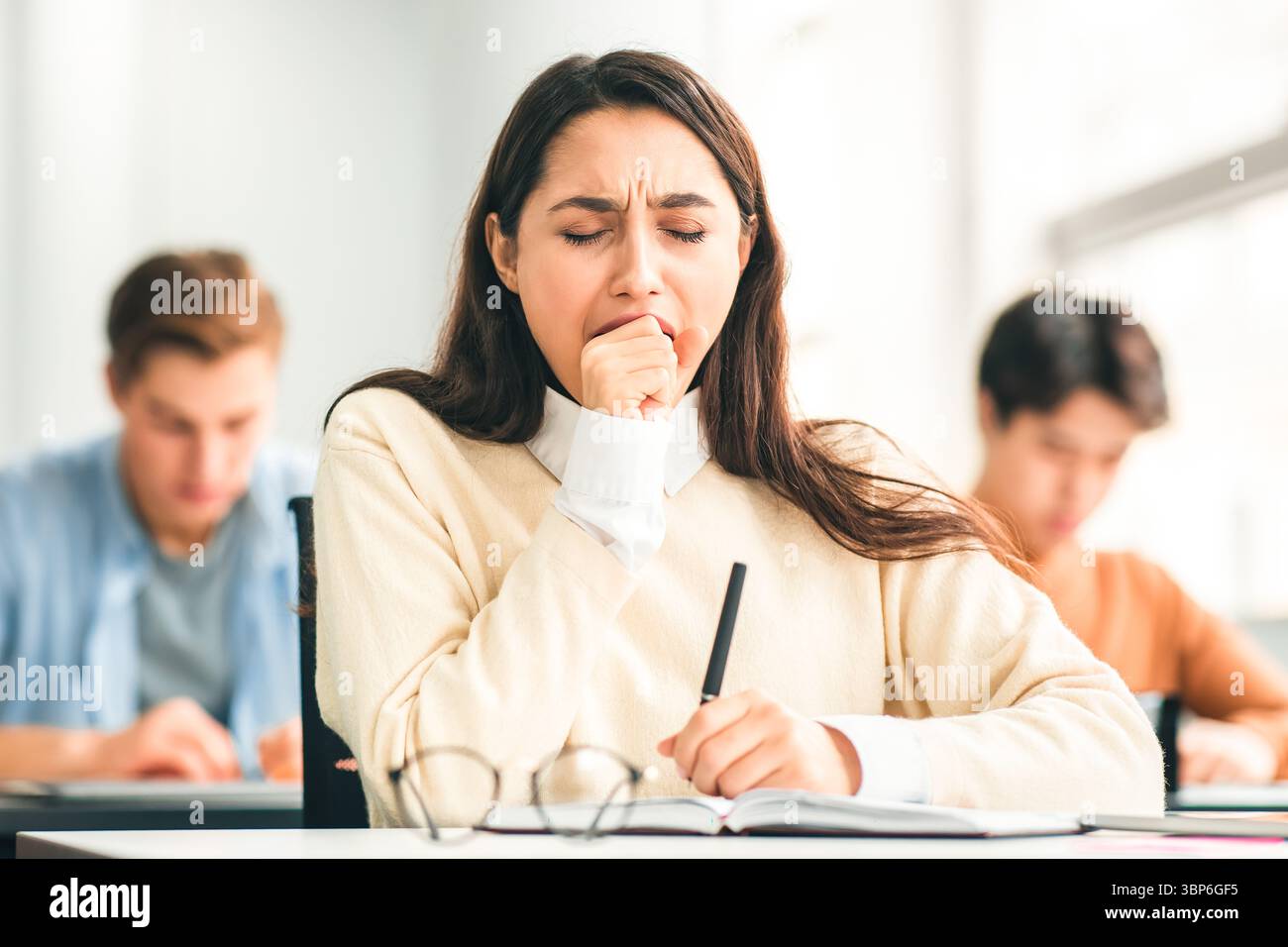 Female student yawning sitting at desk in class Stock Photo - Alamy