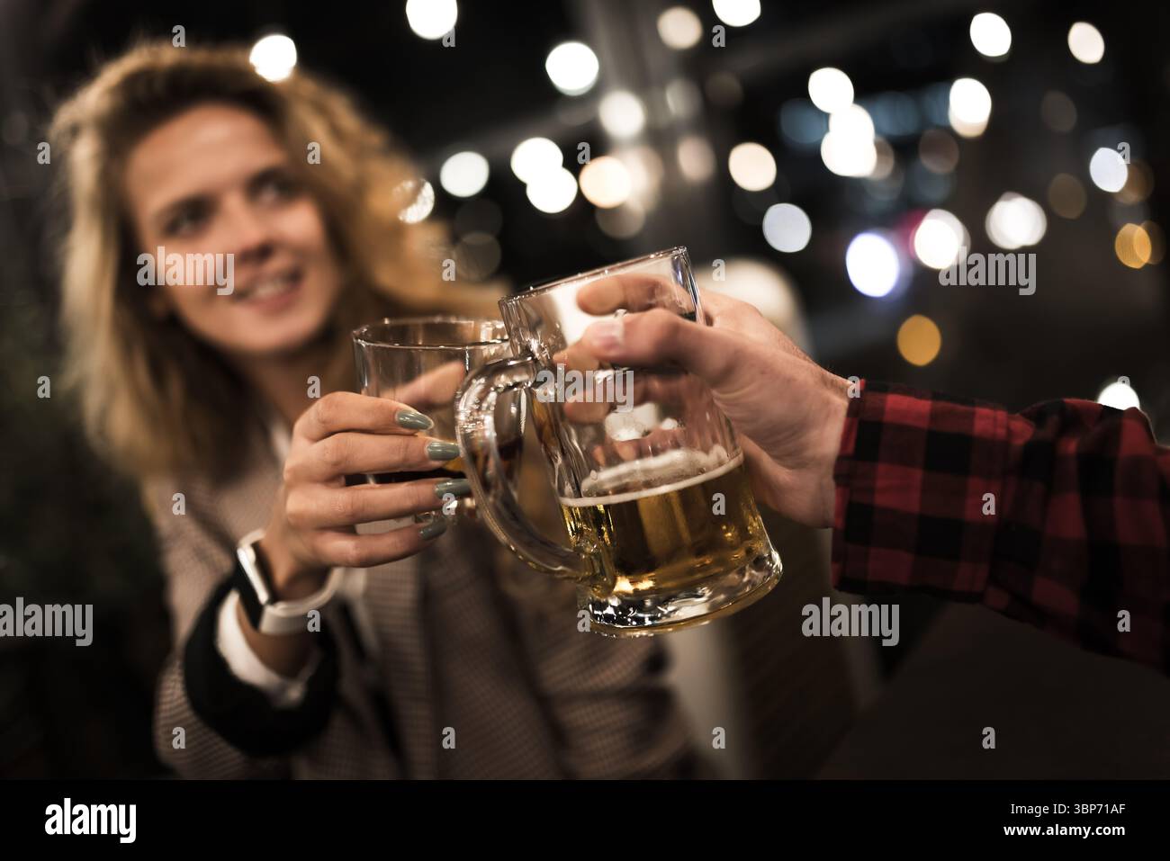 Two friends clinking beer mugs in a warmly lit setting, celebrating ...